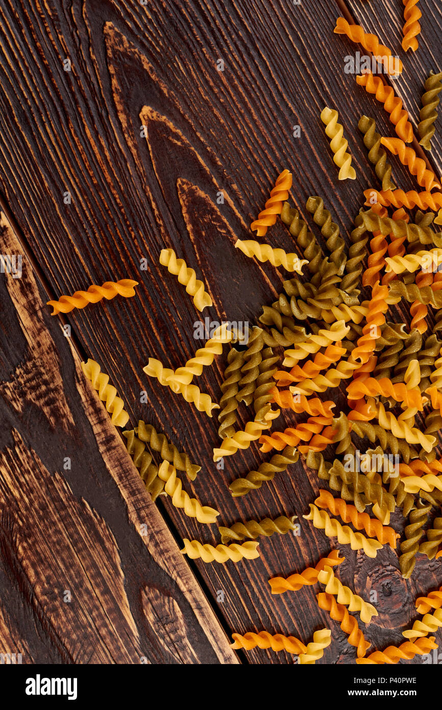 Uncooked spiral pasta, top view. Three-color fusilli pasta on natural ...