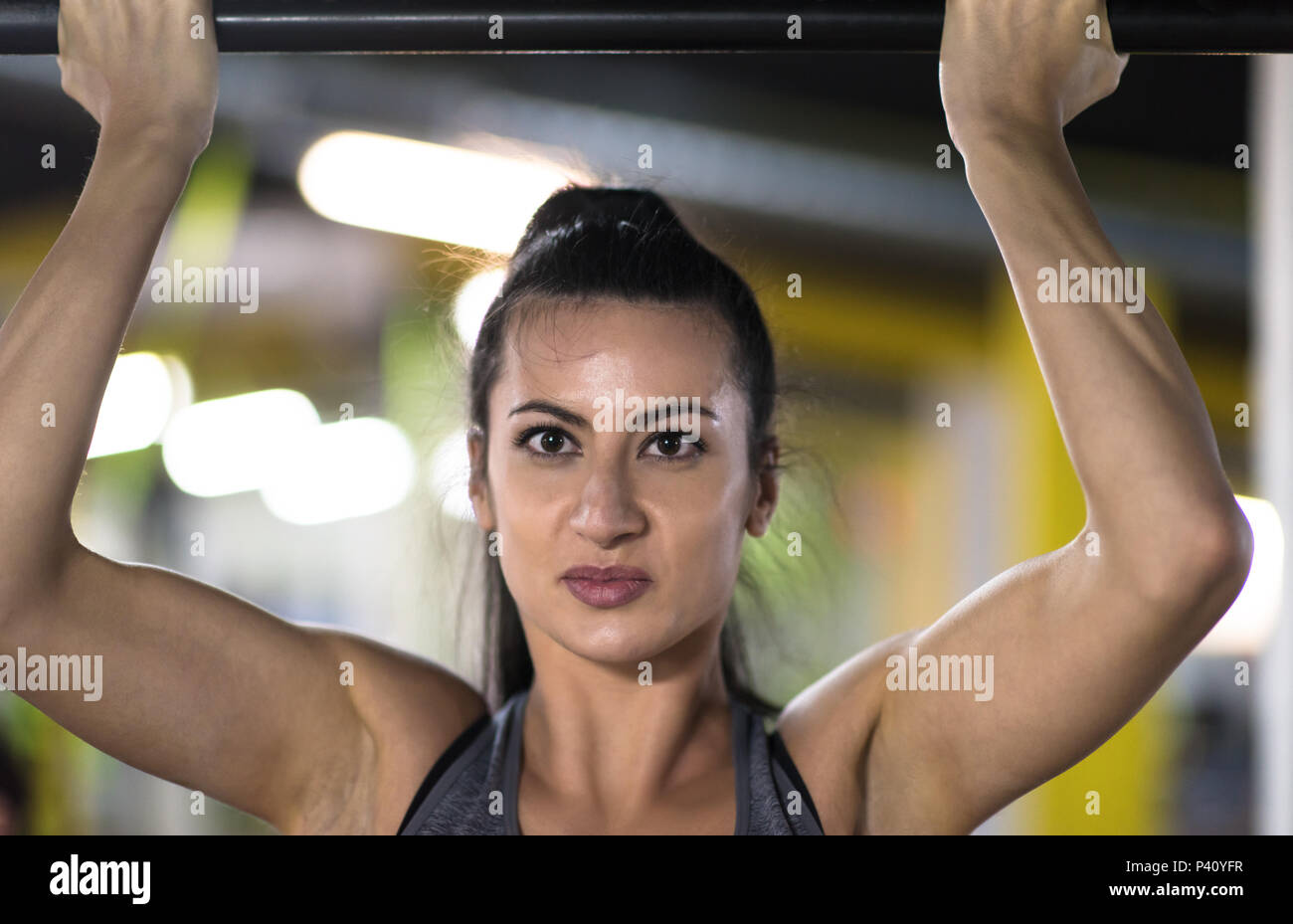 young muscular woman doing pull ups on the horizontal bar as part of ...