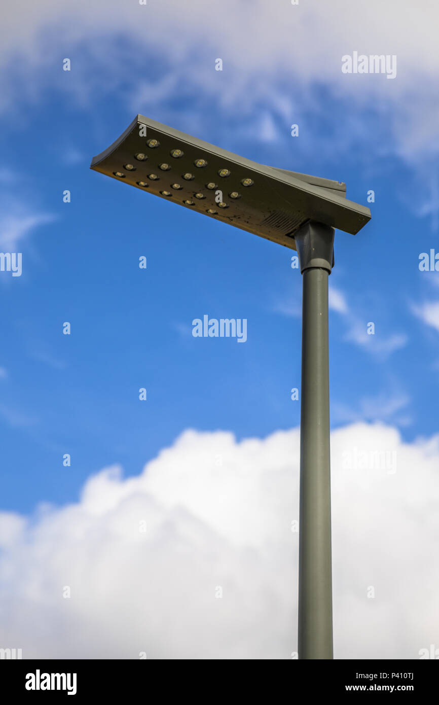 LED street light with black pole and armature aigainst blue summer sky ...