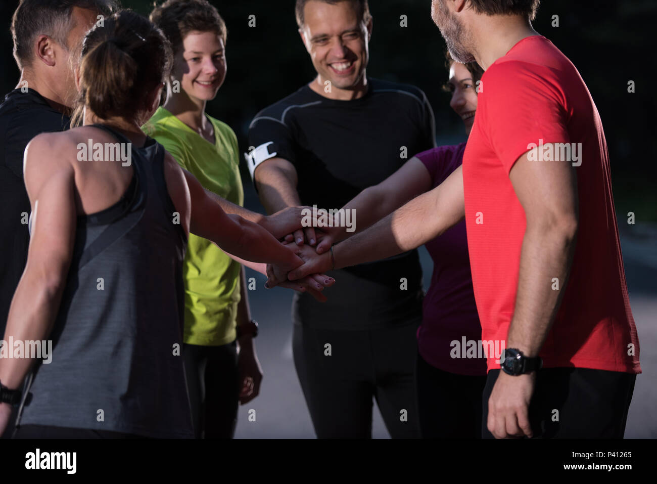 Group of healthy runners giving high five to each other while ...