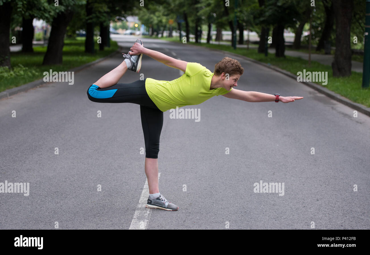 healthy female runner warming up and stretching in city park before ...