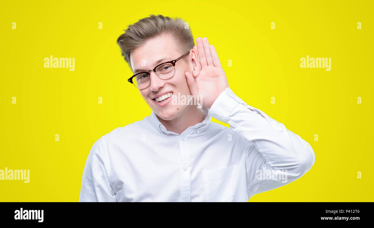 Young handsome blond man smiling with hand over ear listening an ...