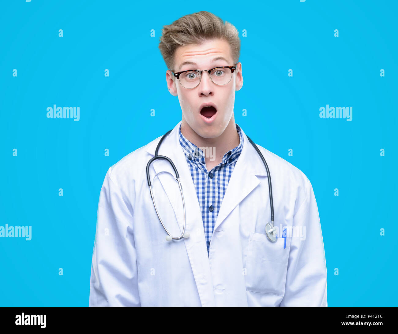 Young handsome blond doctor scared in shock with a surprise face ...