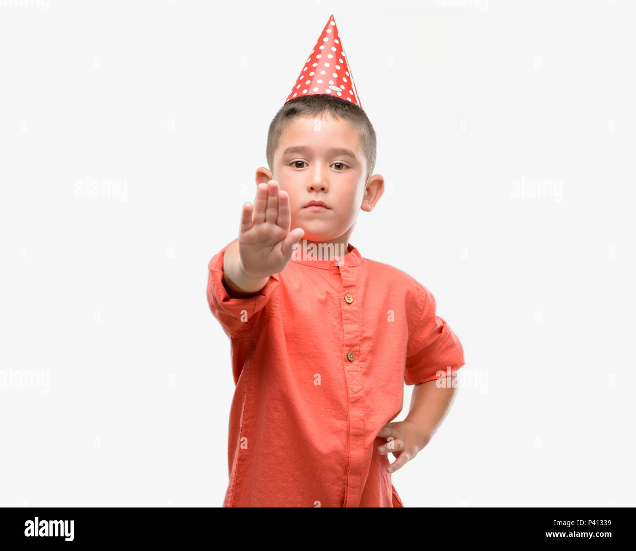 Dark haired little child wearing birthday cap with open hand doing stop ...