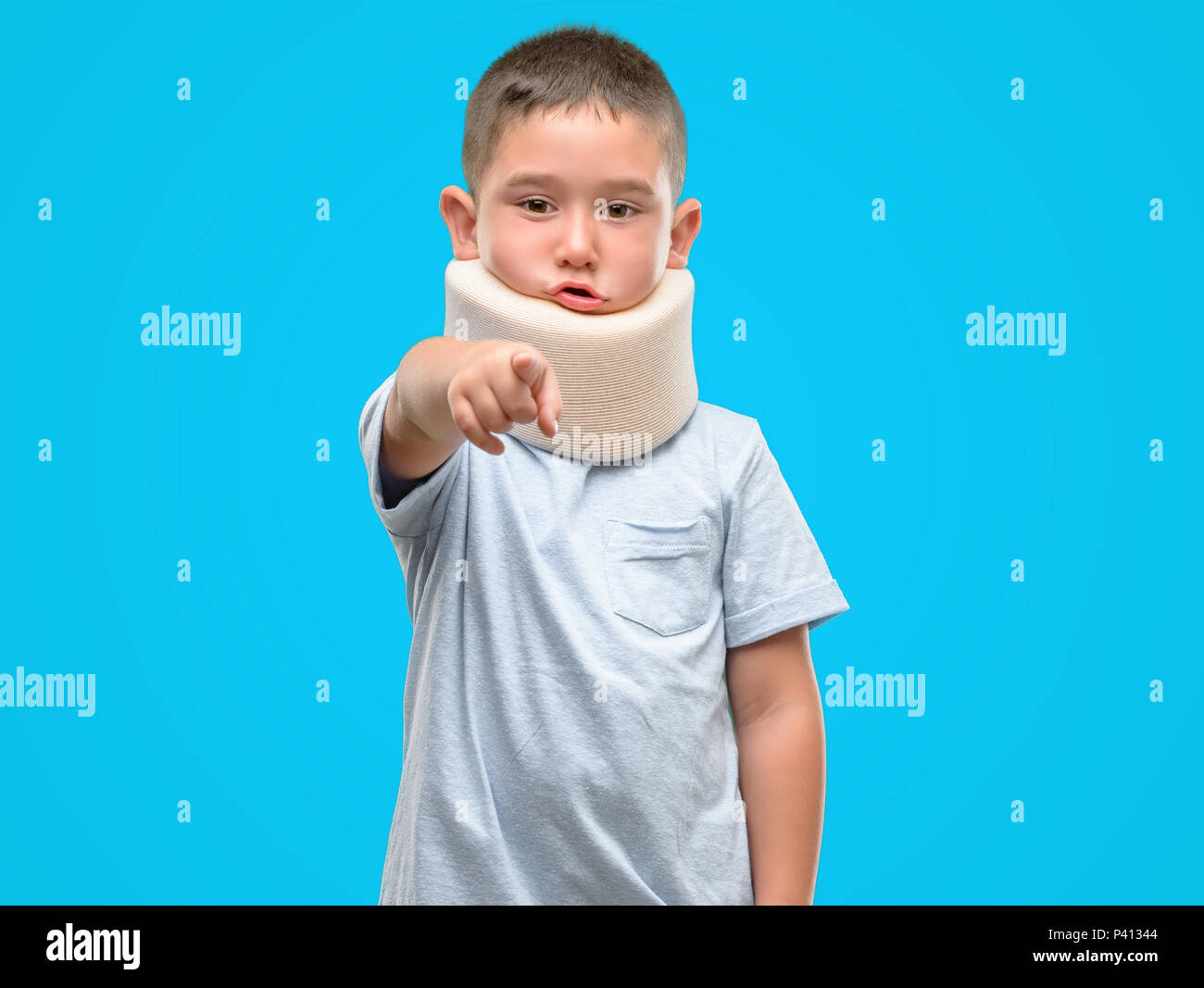 Dark haired little child injured wearing neck collar pointing with ...