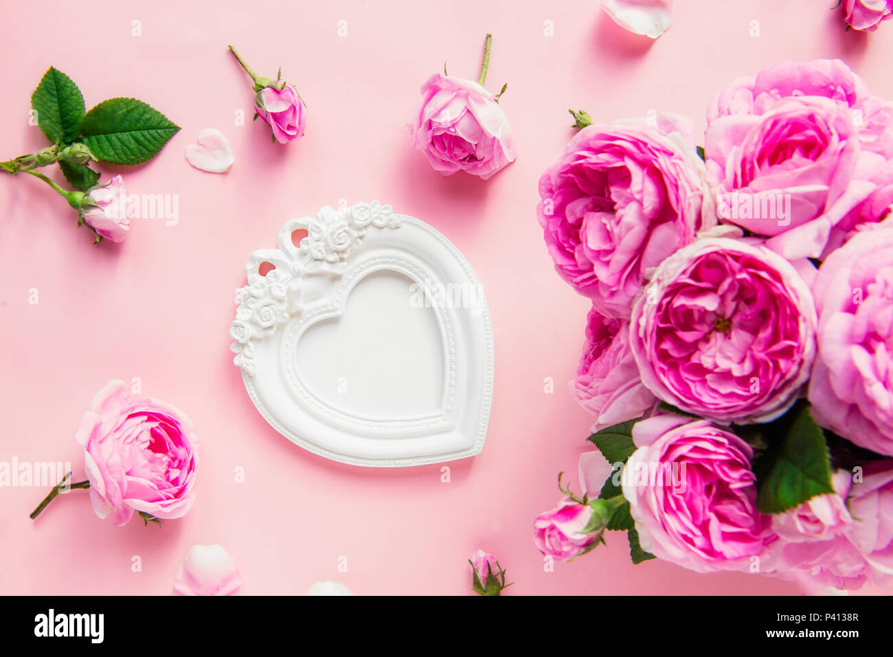 Top view pink tea roses bouquet and white vintage photo frame in shape ...