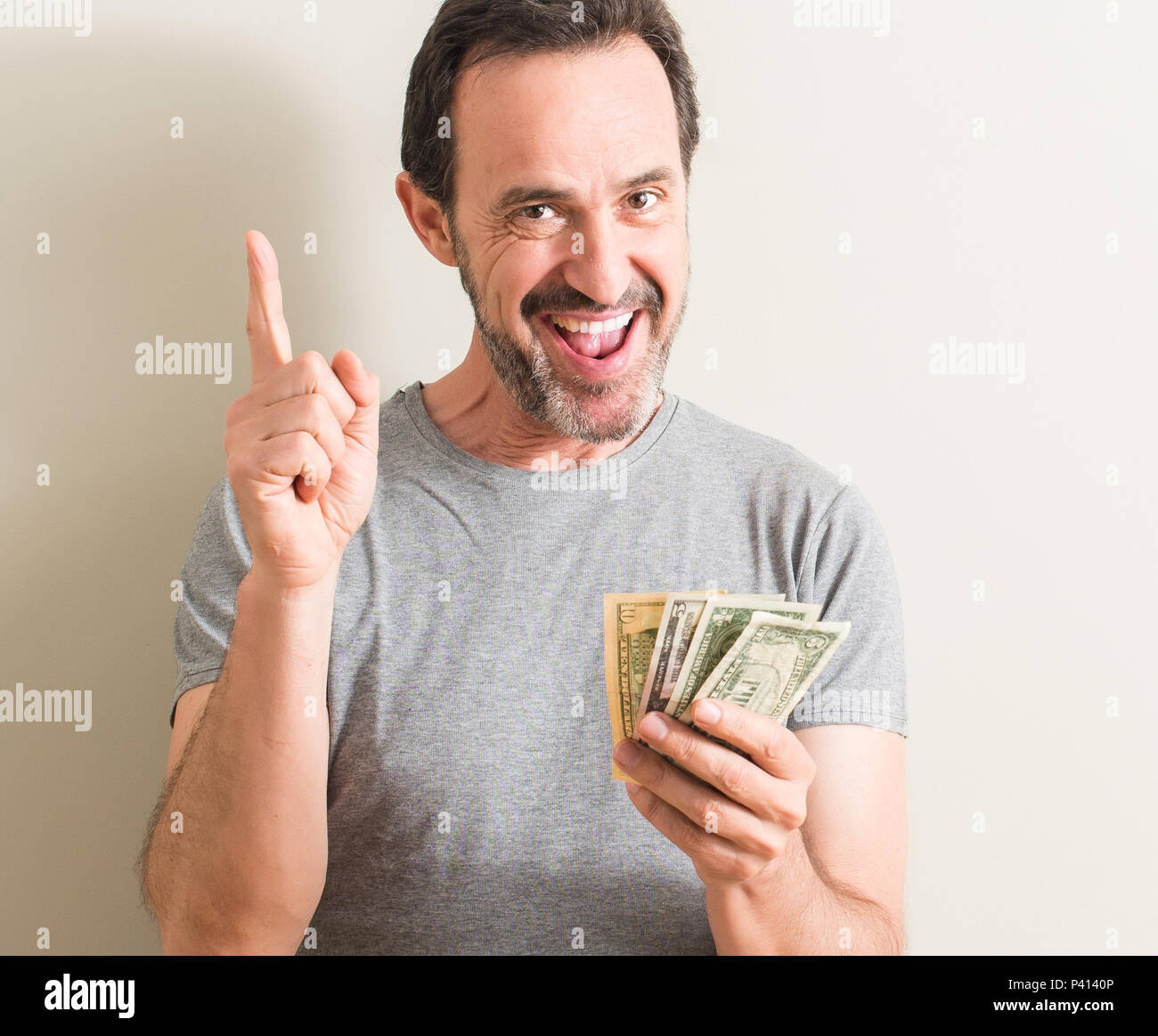 Senior man holding dollar money surprised with an idea or question ...