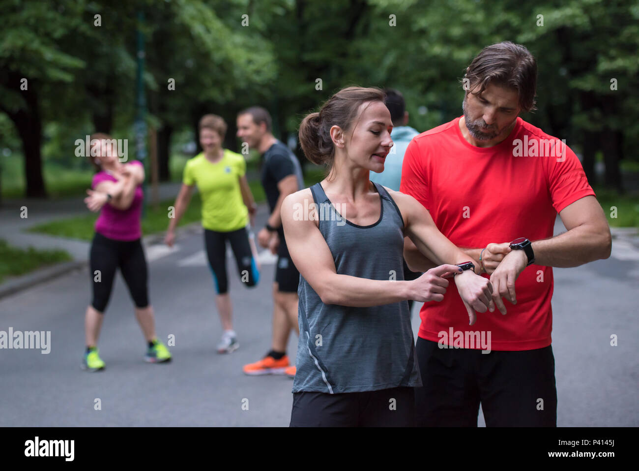Young sporty couple using smart watches starting their timer before ...