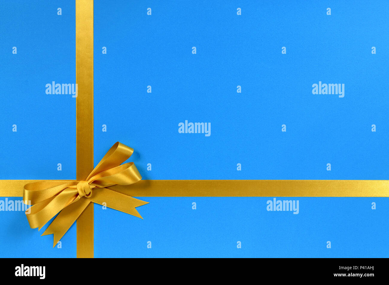 Gold gift ribbon on blue background Stock Photo - Alamy