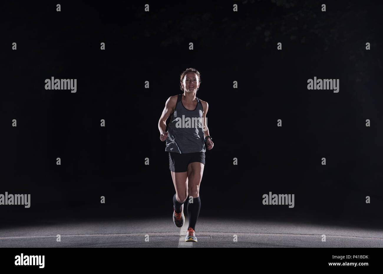 fit muscular female runner training for marathon running at night on ...