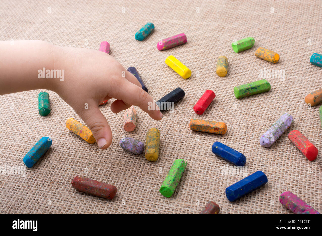 Used color crayons and a toddlers hand pointing Stock Photo - Alamy