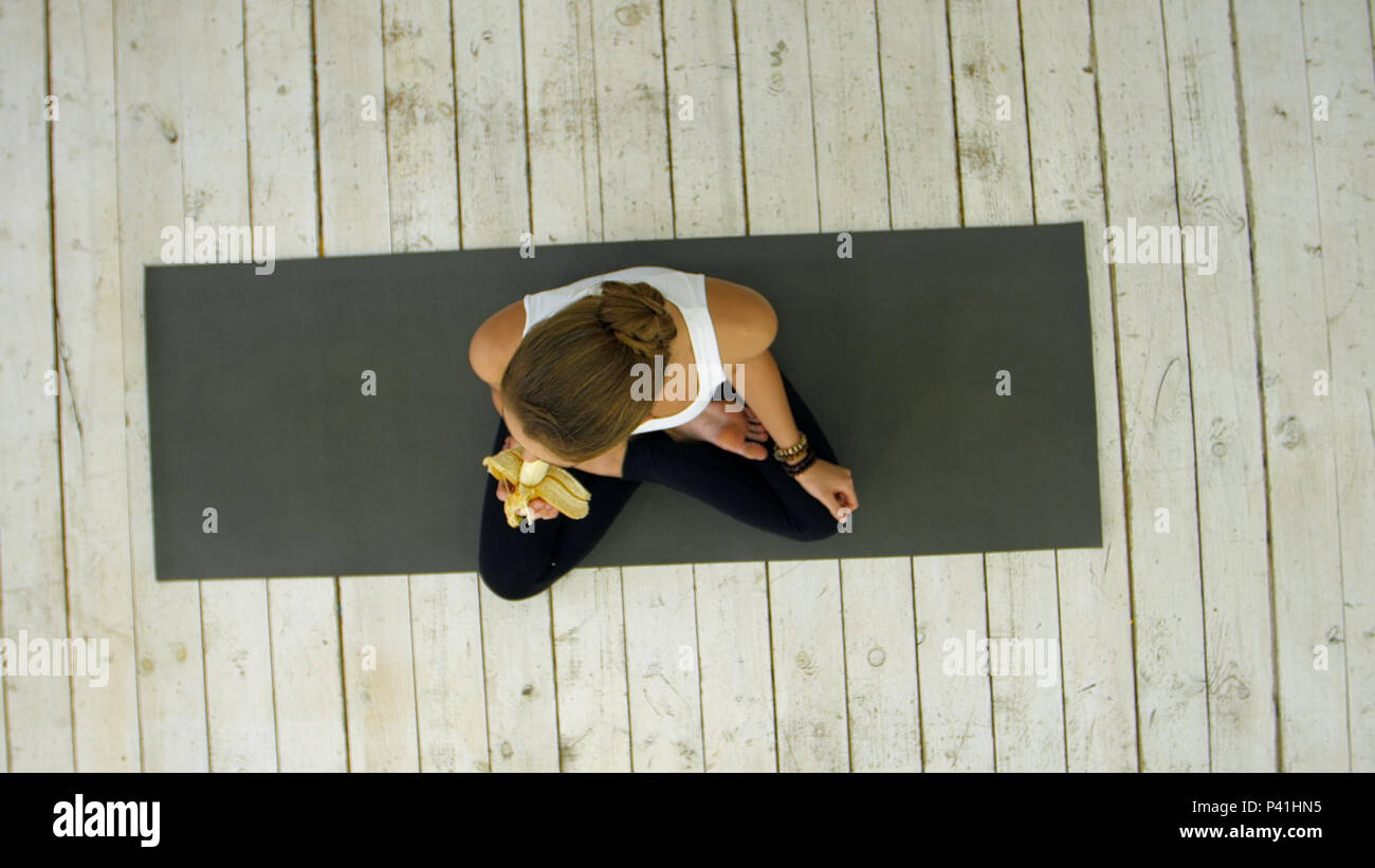 Young woman eating banana after yoga class Stock Photo - Alamy