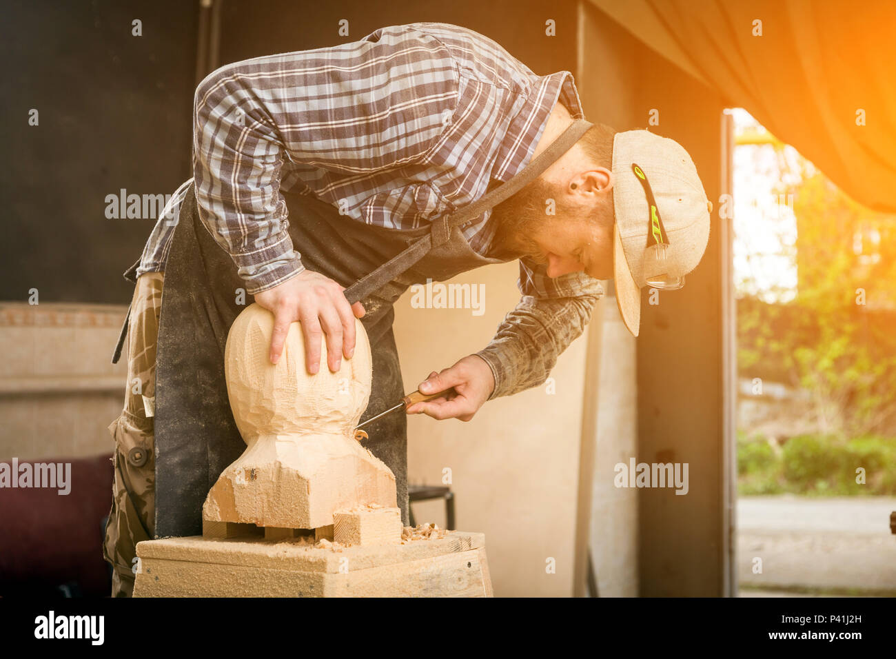 Young man carpenter in a work clothes saws a man's head with a tree ...