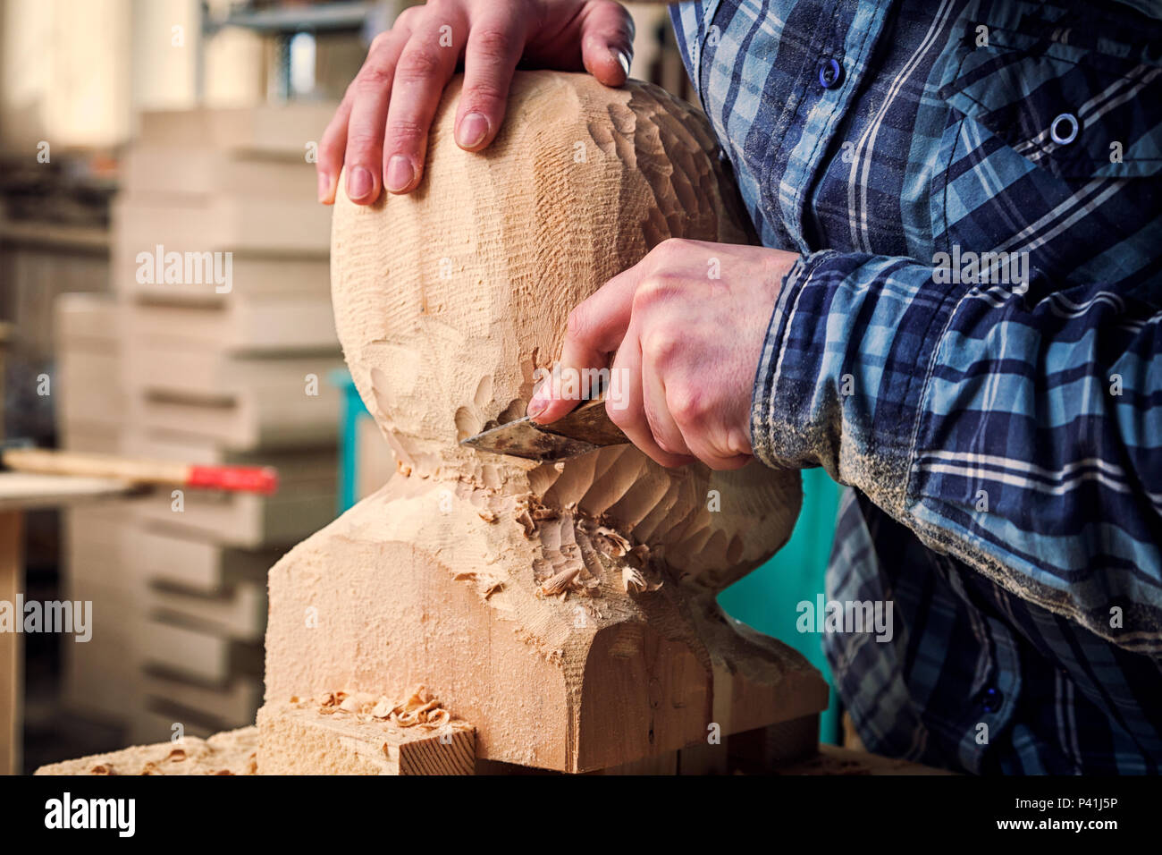Close up young man carpenter in a work clothes saws a man's head with a ...