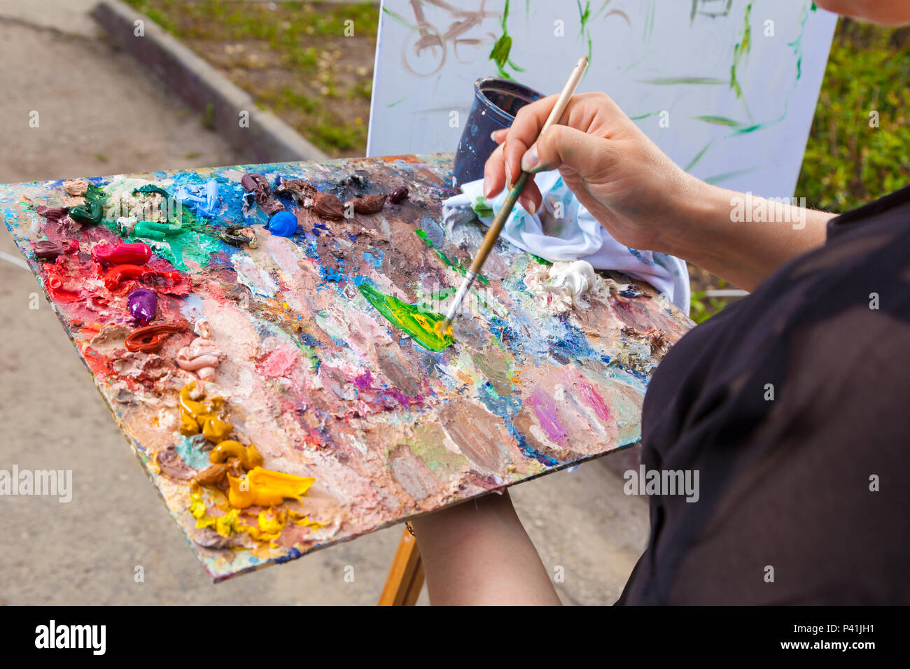 A close-up artist paints on a canvas an urban landscape of a summer ...