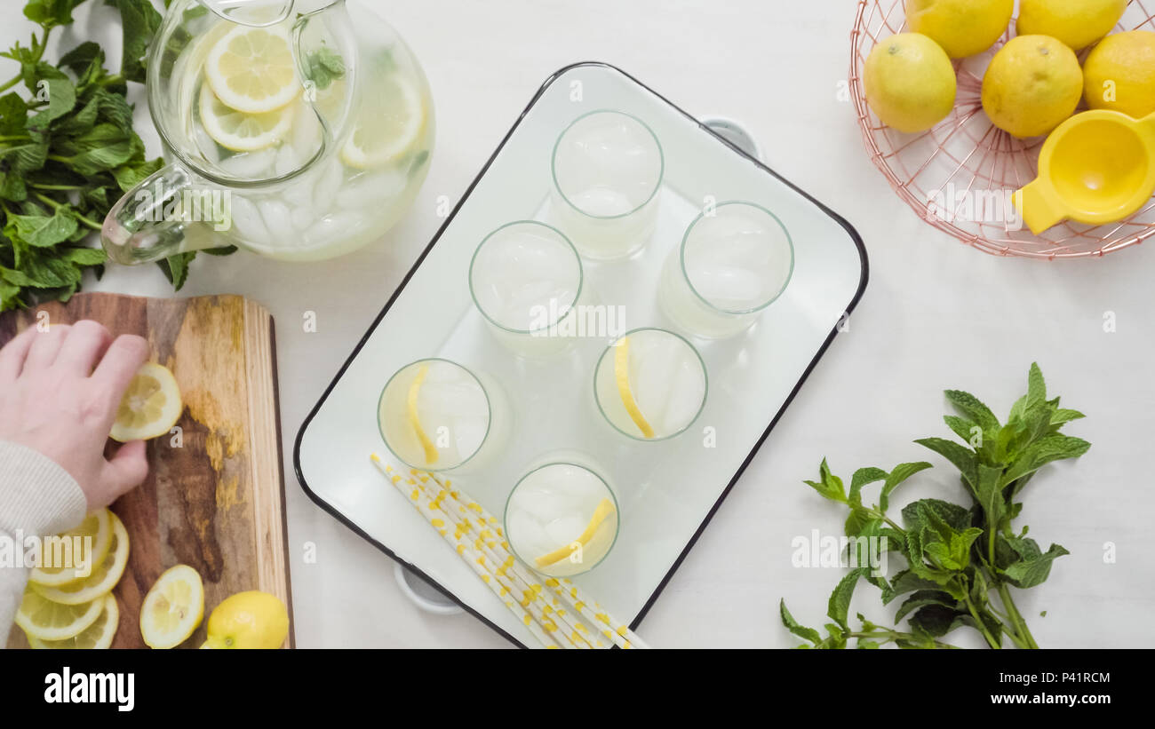 Garnishing traditional lemonade with fresh sliced lemons and mint Stock ...