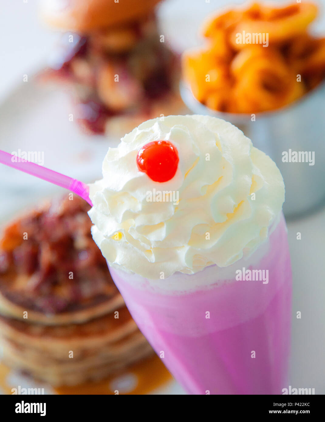 Pink Strawberry Milkshake with burger and fries in the background Stock ...