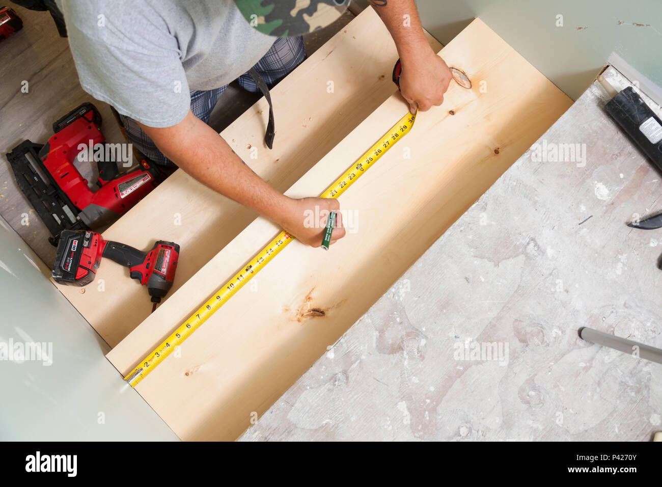 A construction worker using a measuring tape to mark measurements in ...
