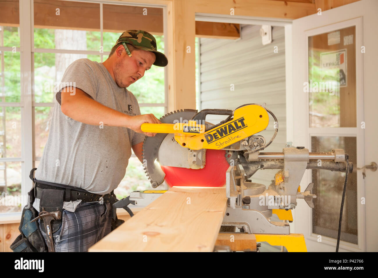A construction worker using a circular saw to cut a wooden plank in ...