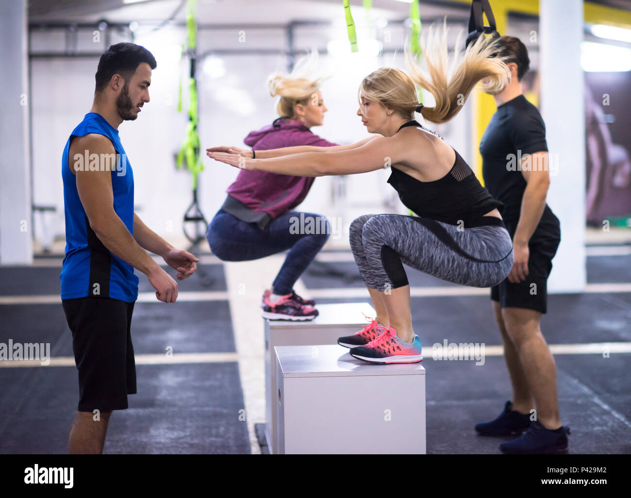 group of young healthy athletic people training jumping on fit box at ...