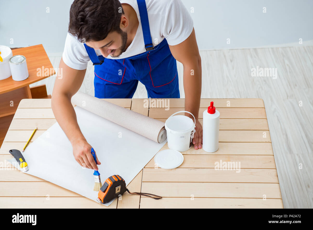 Worker working on wallpaper during refurbishment Stock Photo - Alamy
