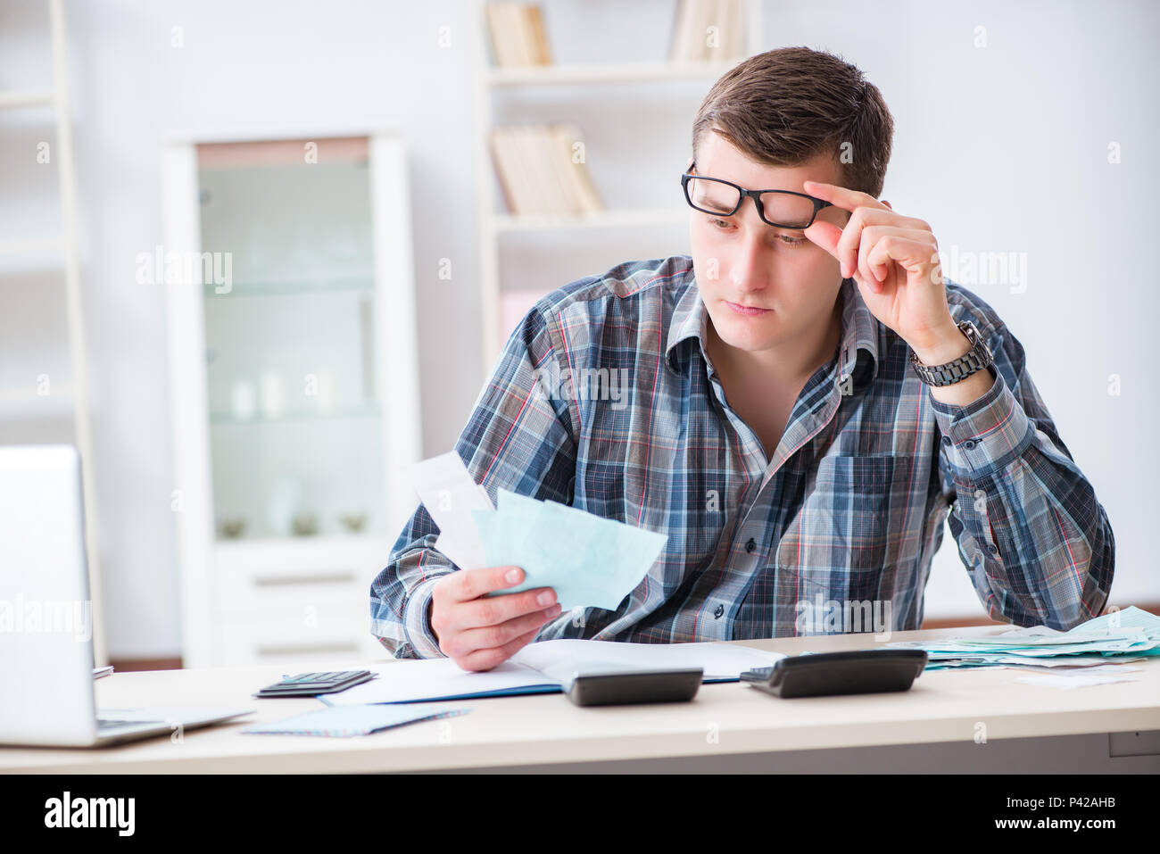 Young man frustrated at his house and tax bills Stock Photo - Alamy