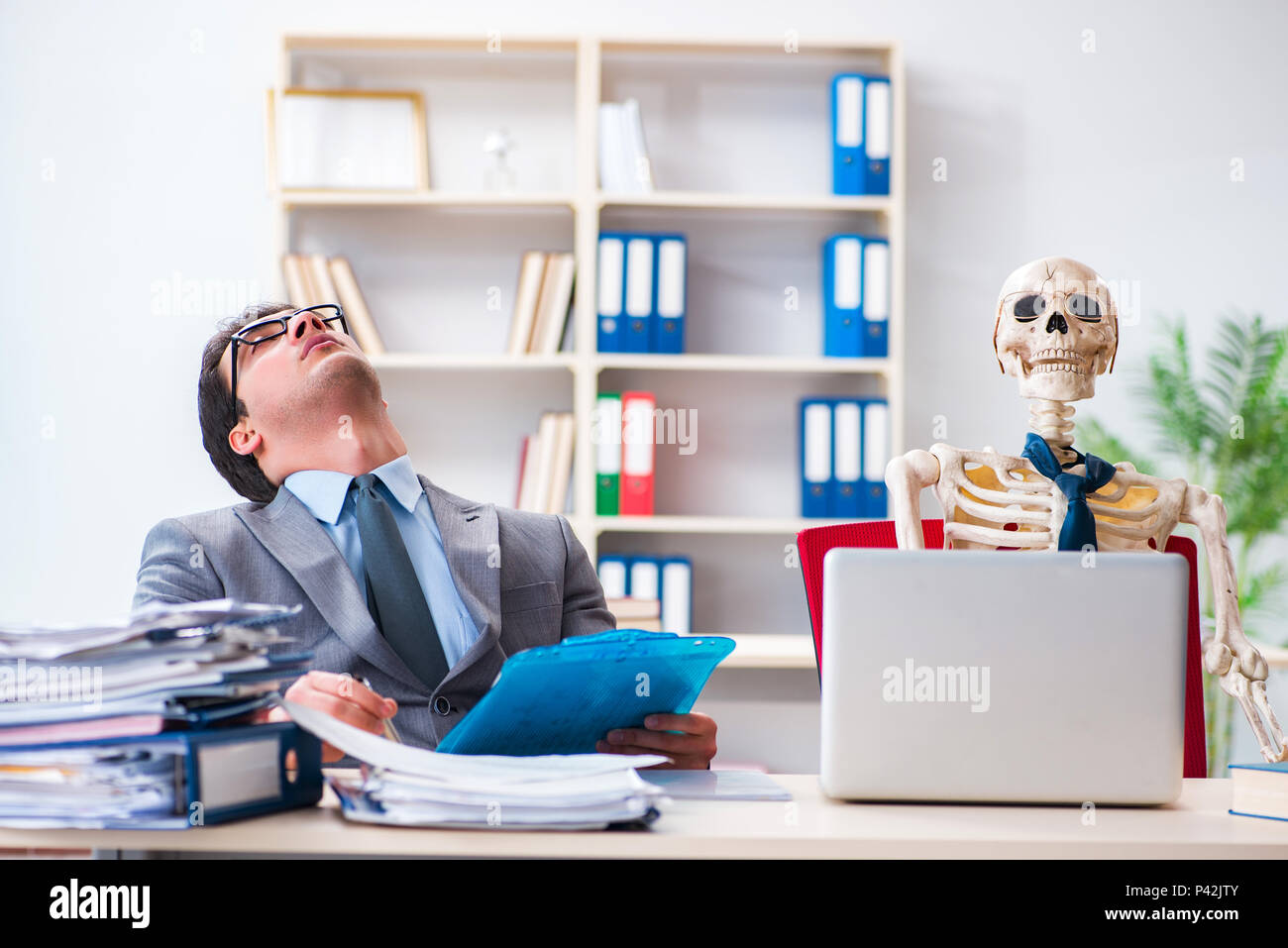 Businessman working with skeleton in office Stock Photo - Alamy