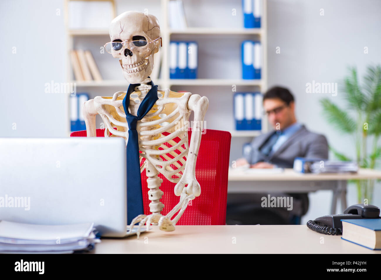 Businessman working with skeleton in office Stock Photo - Alamy