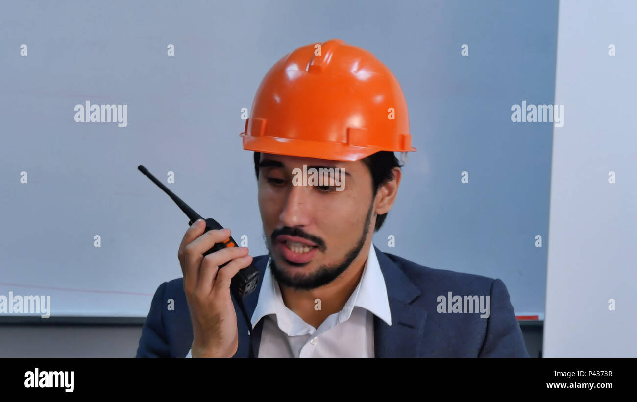 Businessman in helmet talking at radio set sitting in office Stock ...