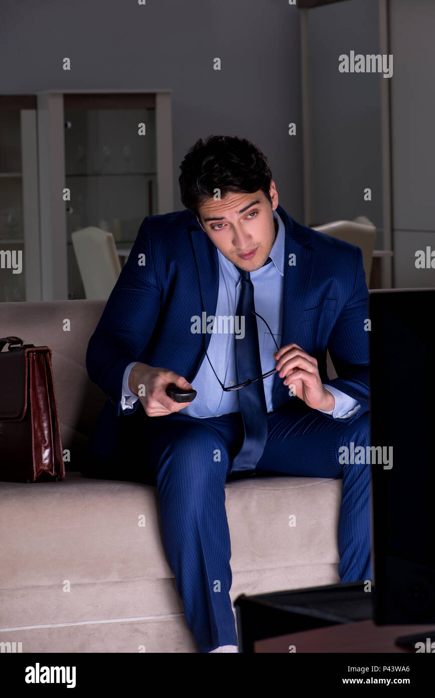 Businessman watching tv at night late Stock Photo - Alamy