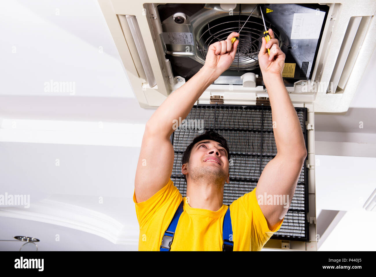 Repairman repairing ceiling air conditioning unit Stock Photo - Alamy