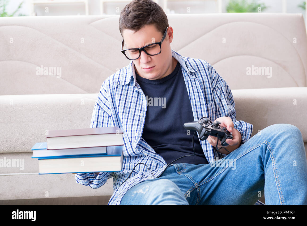Young student trying to balance studying and playing games Stock Photo ...