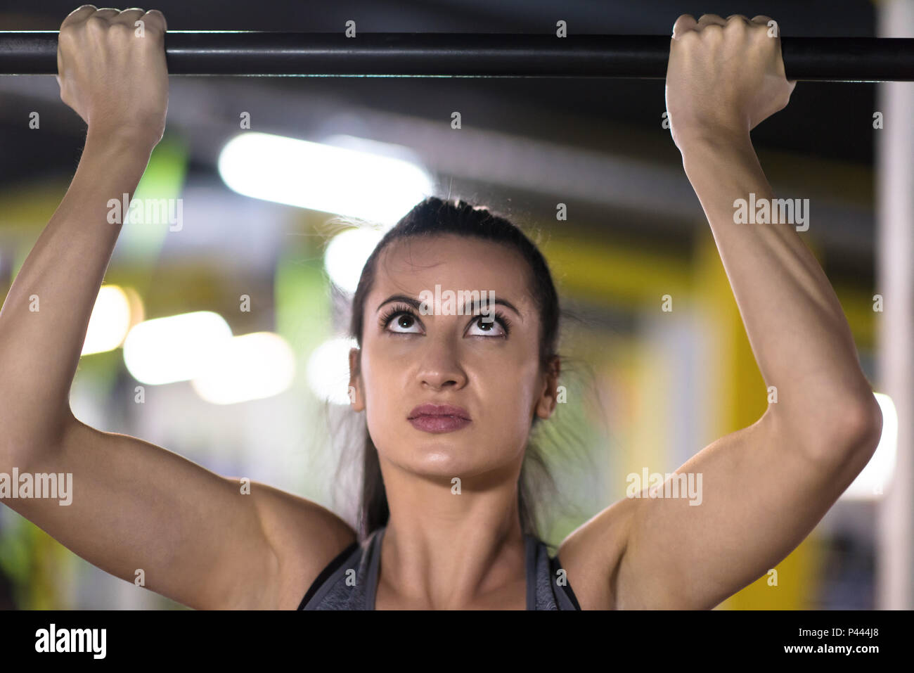 young muscular woman doing pull ups on the horizontal bar as part of ...