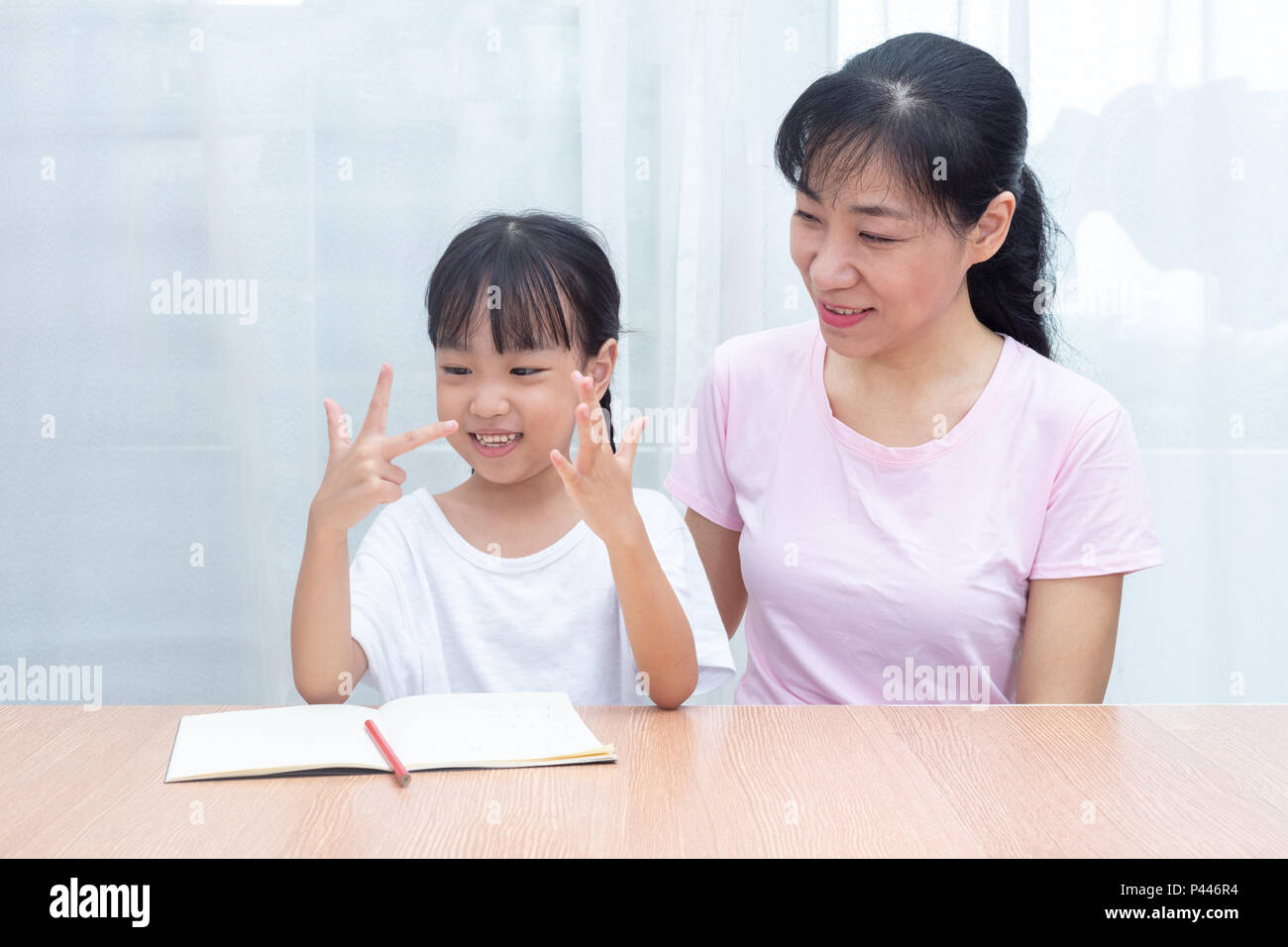 Asian Chinese mother teaching daughter mathematics by counting fingers ...