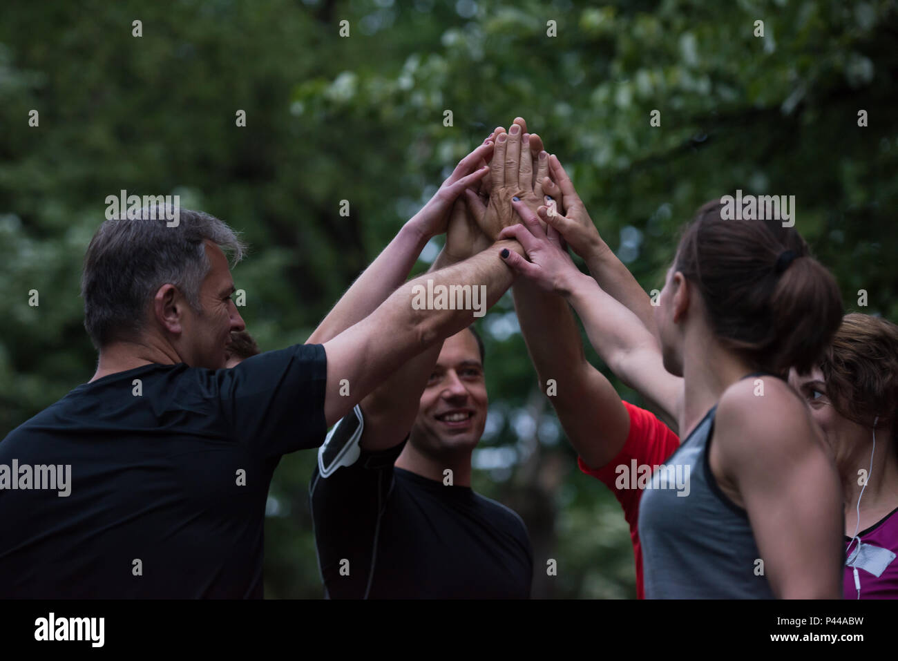 Group of healthy runners giving high five to each other while ...