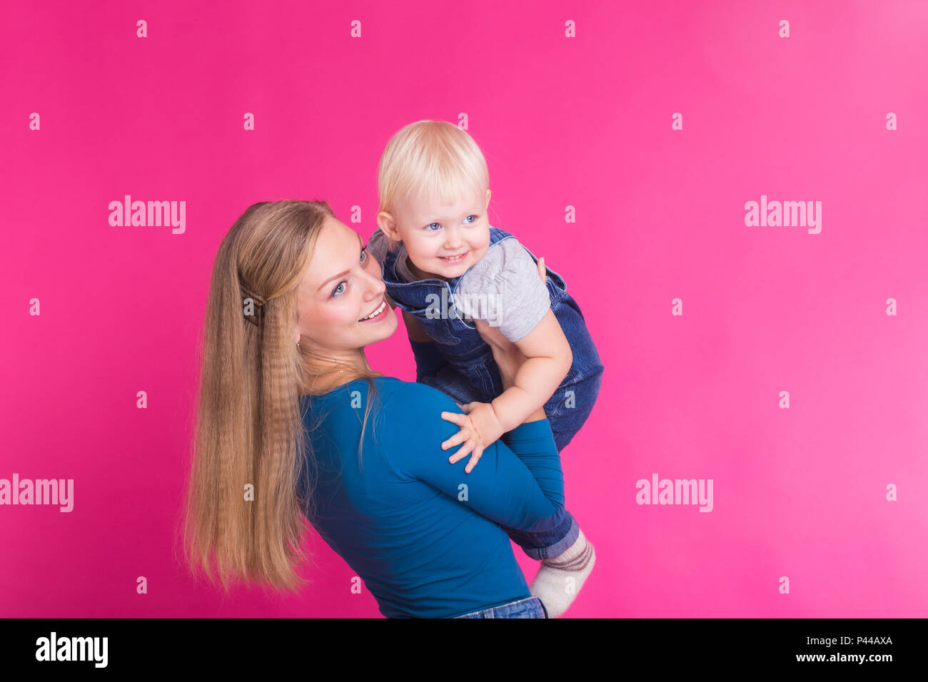 happy little girl and her mother having fun over pink background Stock ...