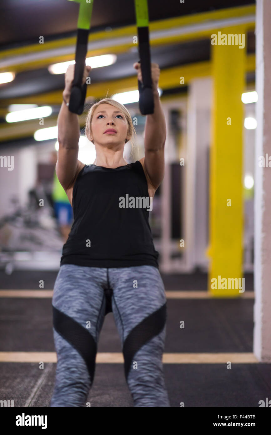 young athlete woman working out pull ups with gymnastic rings at the ...