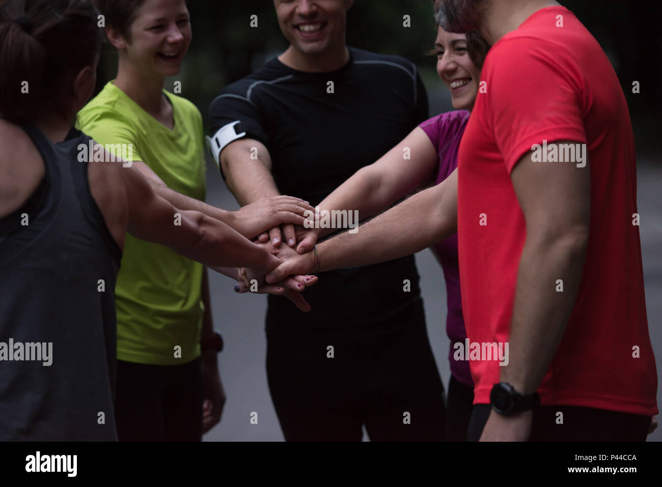 Group of healthy runners giving high five to each other while ...