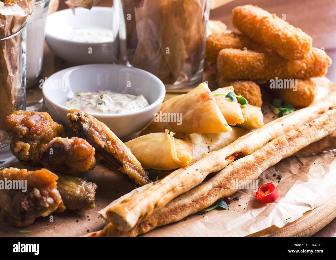 Spicy baked chicken wings, bread sticks with appetizers and sauces on ...