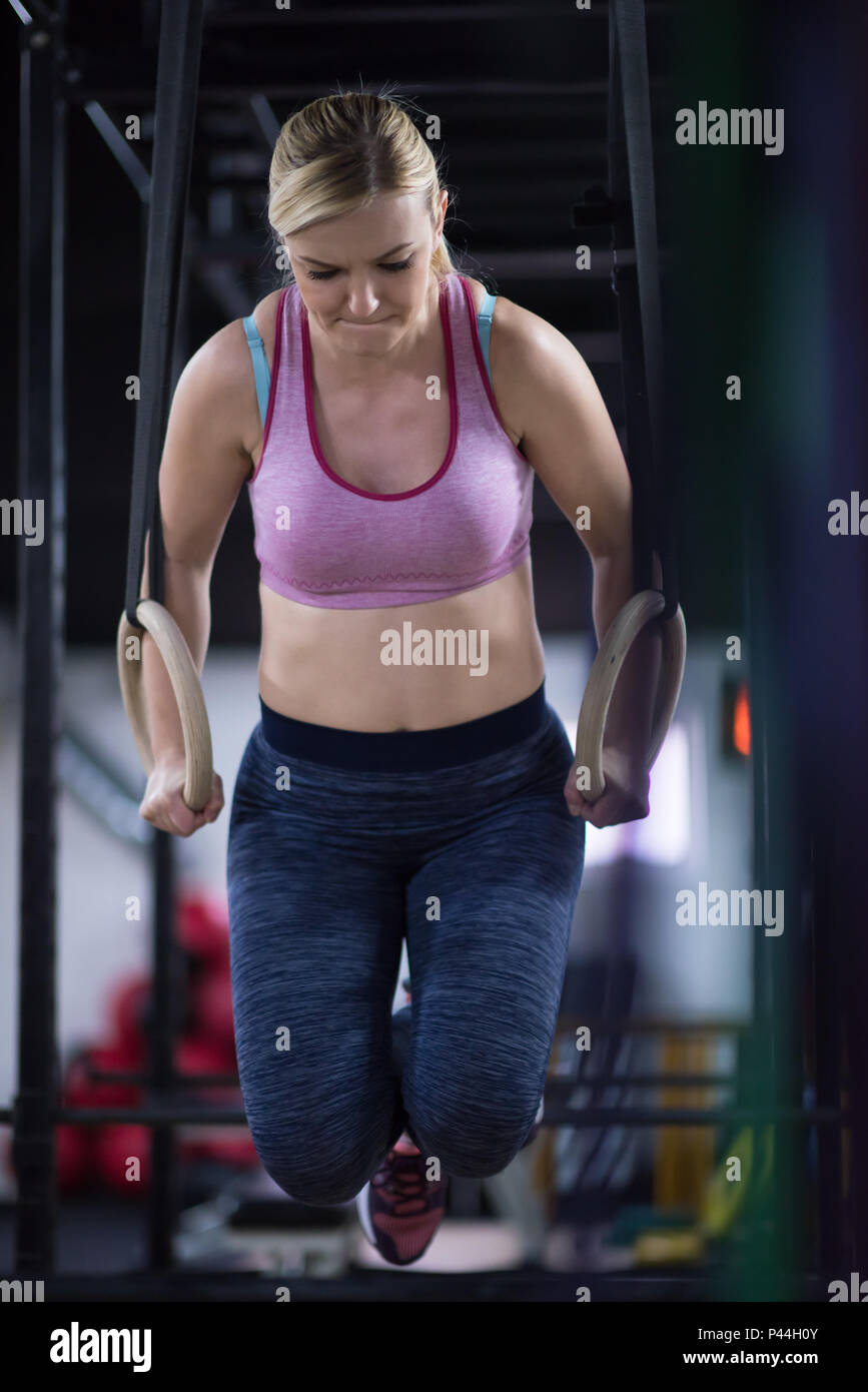 young athlete woman working out pull ups with gymnastic rings at the ...