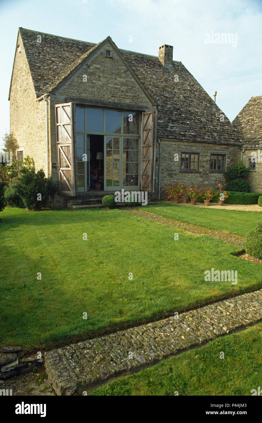 Exterior of country barn conversion with lawn edged by stone path Stock ...
