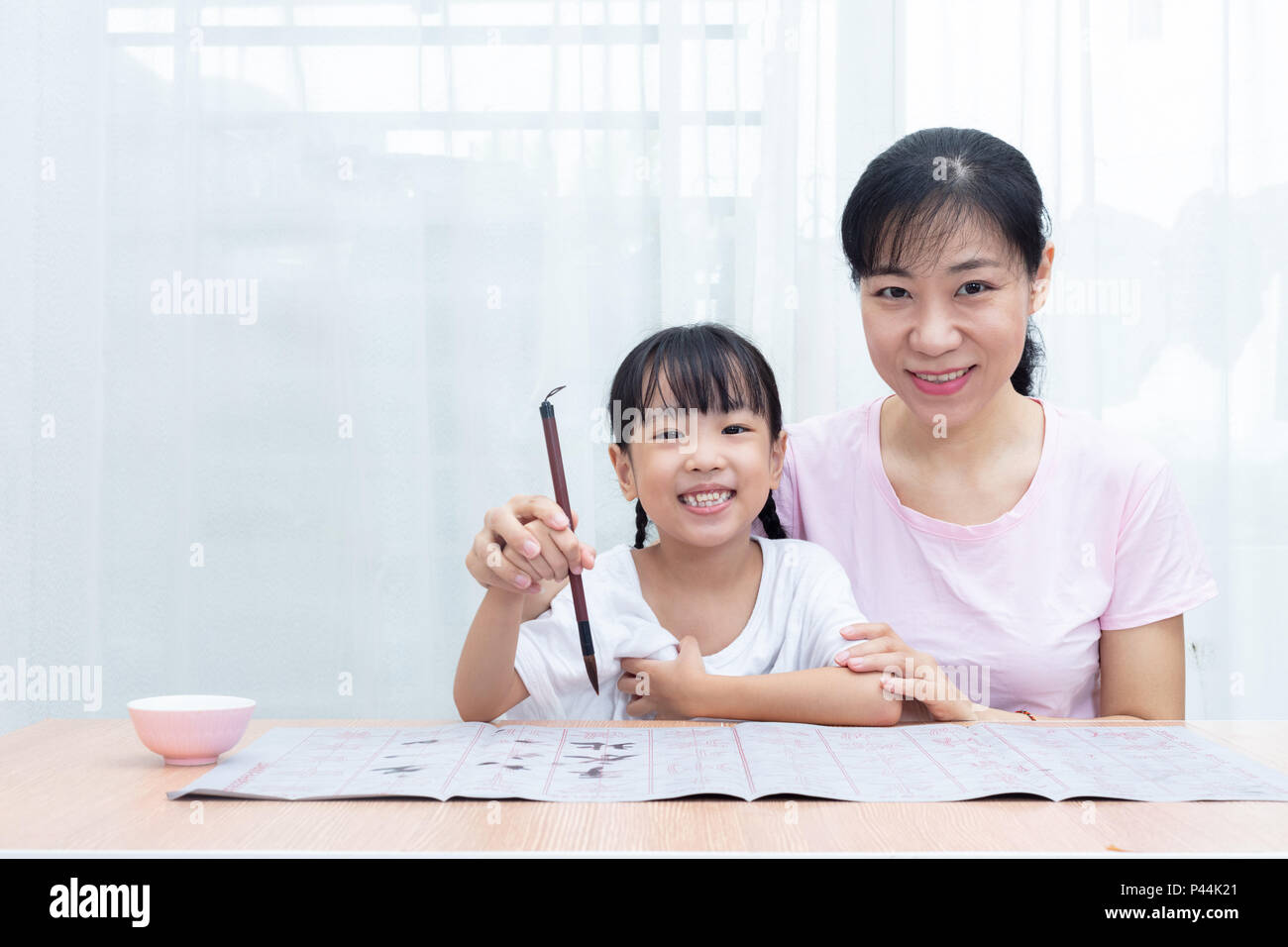 Asian Chinese mother teaching daughter practice Chinese calligraphy at ...