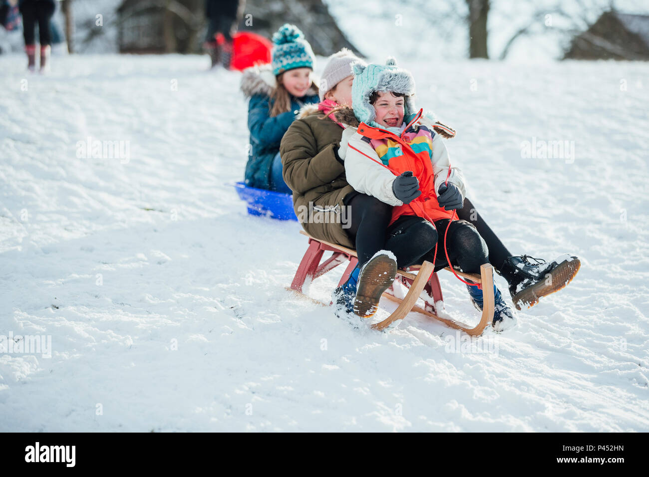Children are having a race down a hill on different types of sleds ...