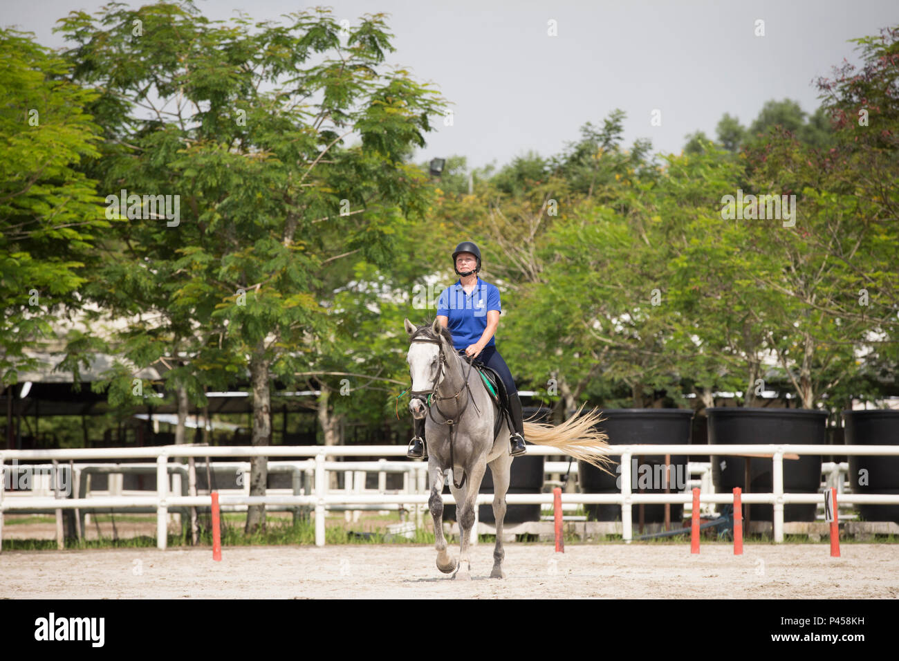 A western woman riding her horse around a paddock at a riding school in ...