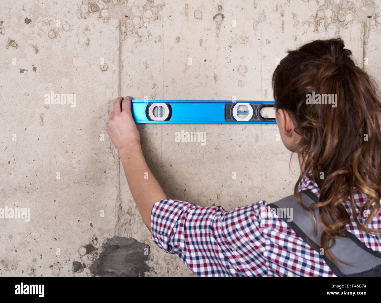 Young woman working with blue builder's standard level in house under ...