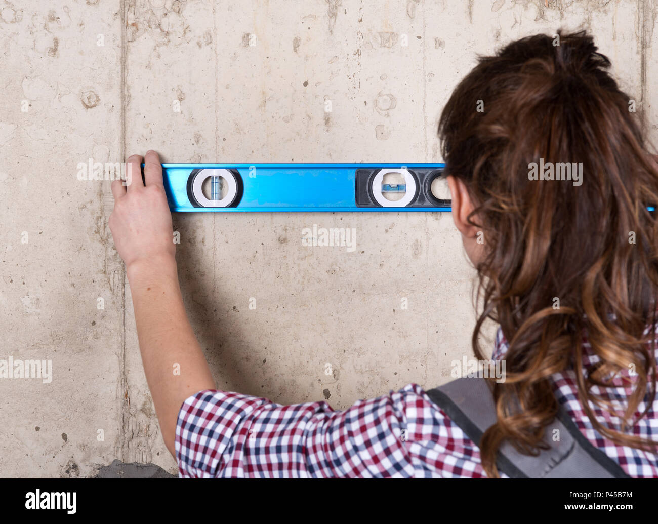 Young woman working with blue builder's standard level in house under ...