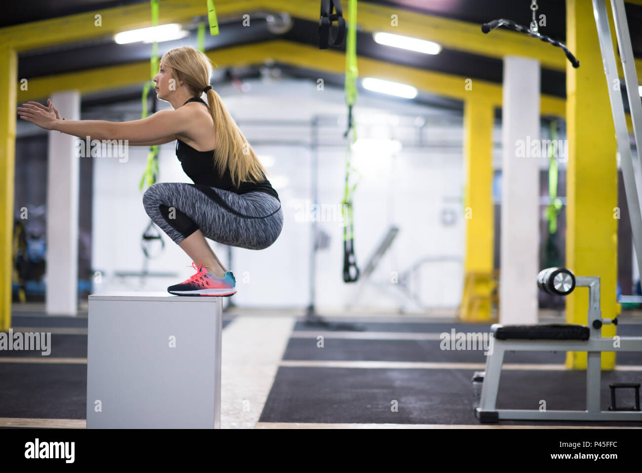 young athletic woman training jumping on fit box at cross fitness gym ...