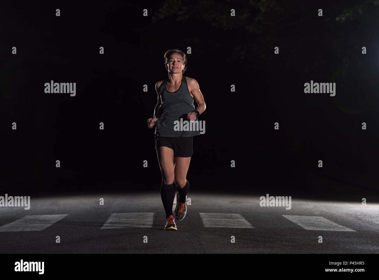 fit muscular female runner training for marathon running at night on ...