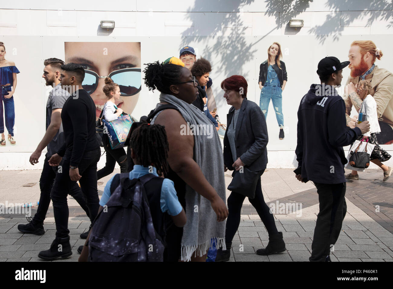 Multicultural scene of people out walking past a series of posters for ...
