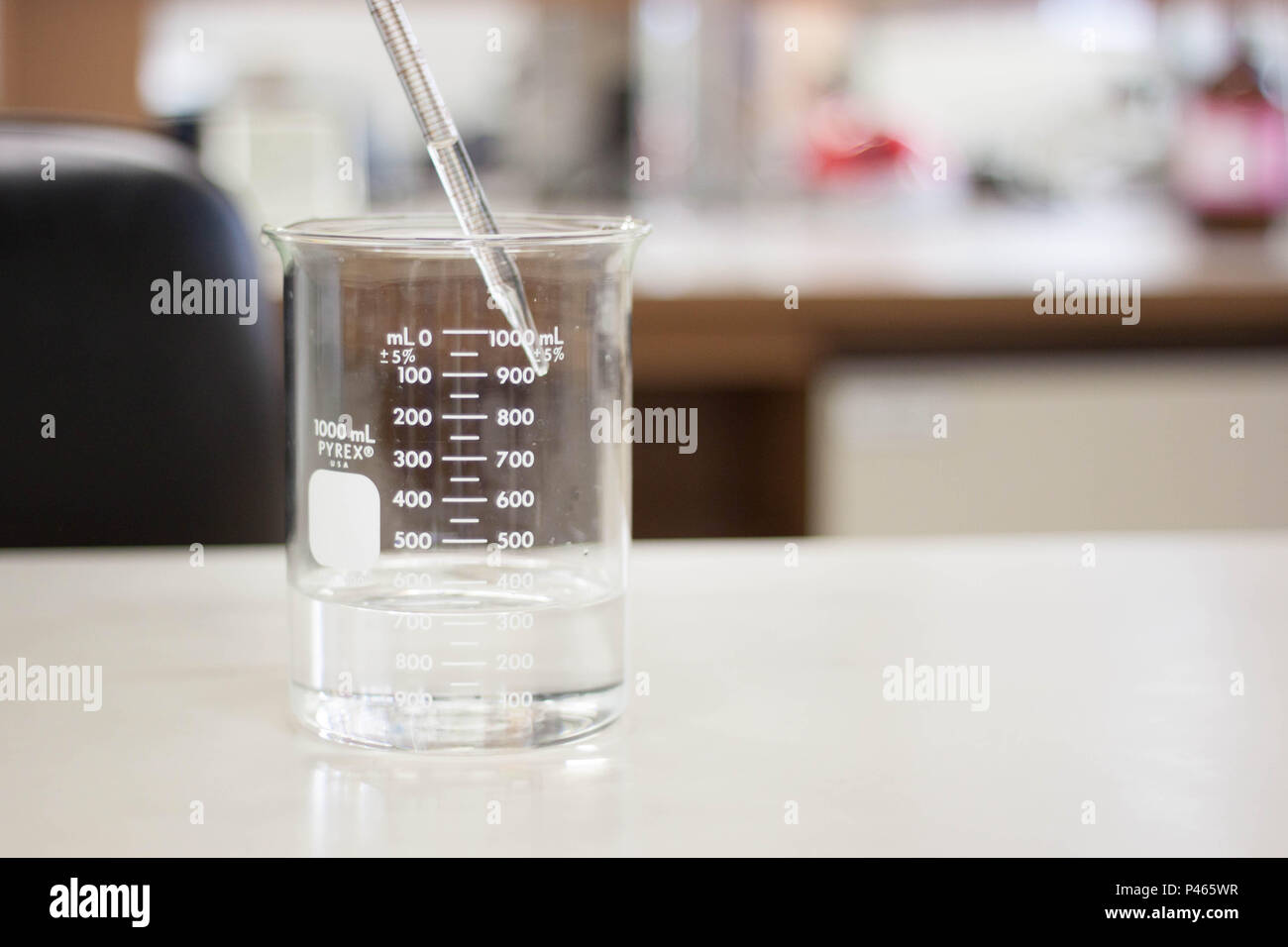Becker com pipeta e líquido transparente marcando 300 ml em bancada de ...